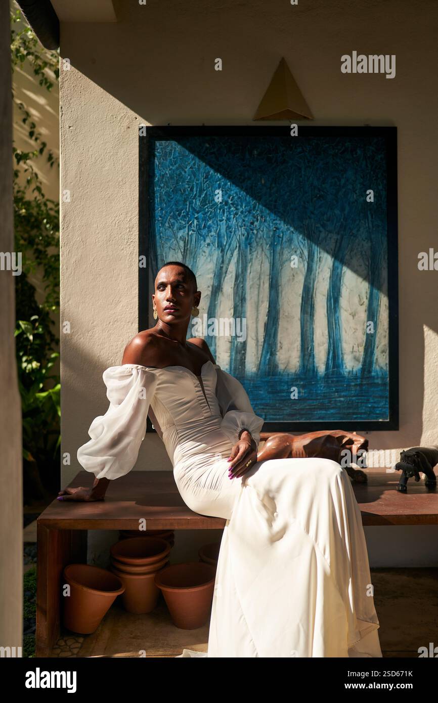 Androgynous person in white wedding dress, sunlit villa. Fluid identity ...