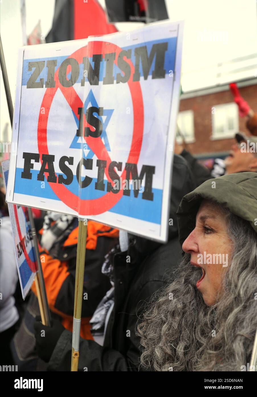A protester holds up a sign saying ‘Zionism Is Fascism’ outside the UAV ...