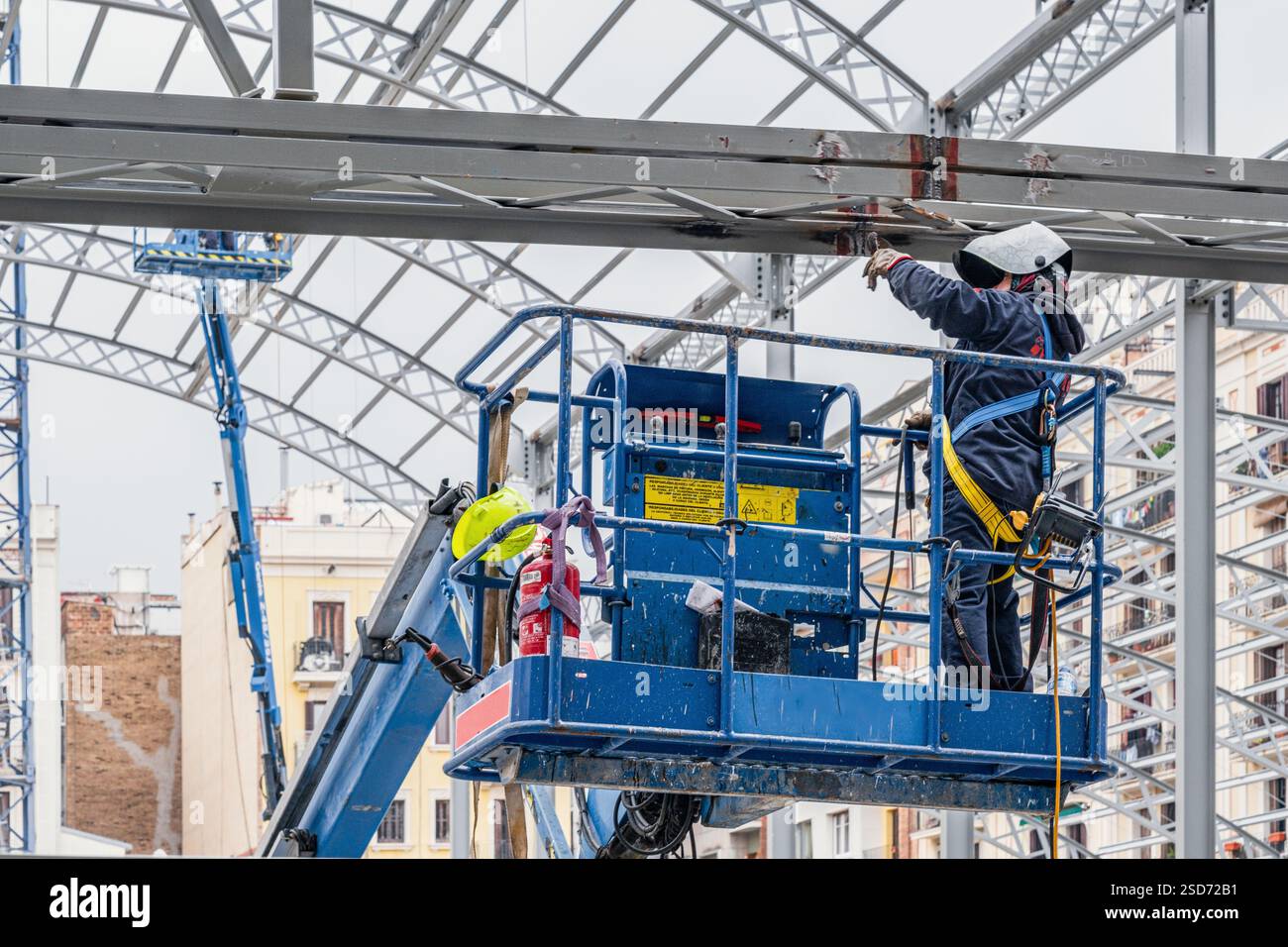 A welder standing on an aerial work platform checks the work performed ...