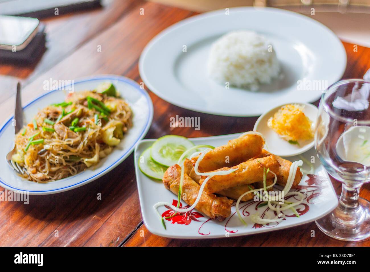 A traditional Filipino lunch spread of rice, lumpia, and pansit served ...