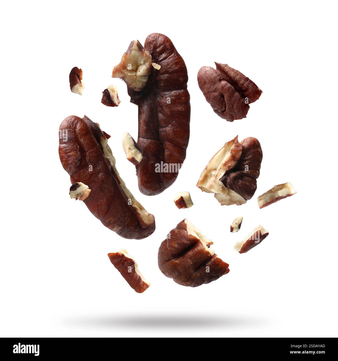 Broken pecan nuts in air on white background Stock Photo - Alamy