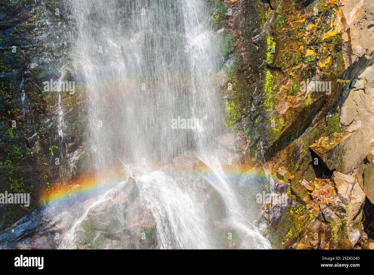 Waterfall Cascading Down a Rocky Cliff with a Rainbow Stock Photo - Alamy
