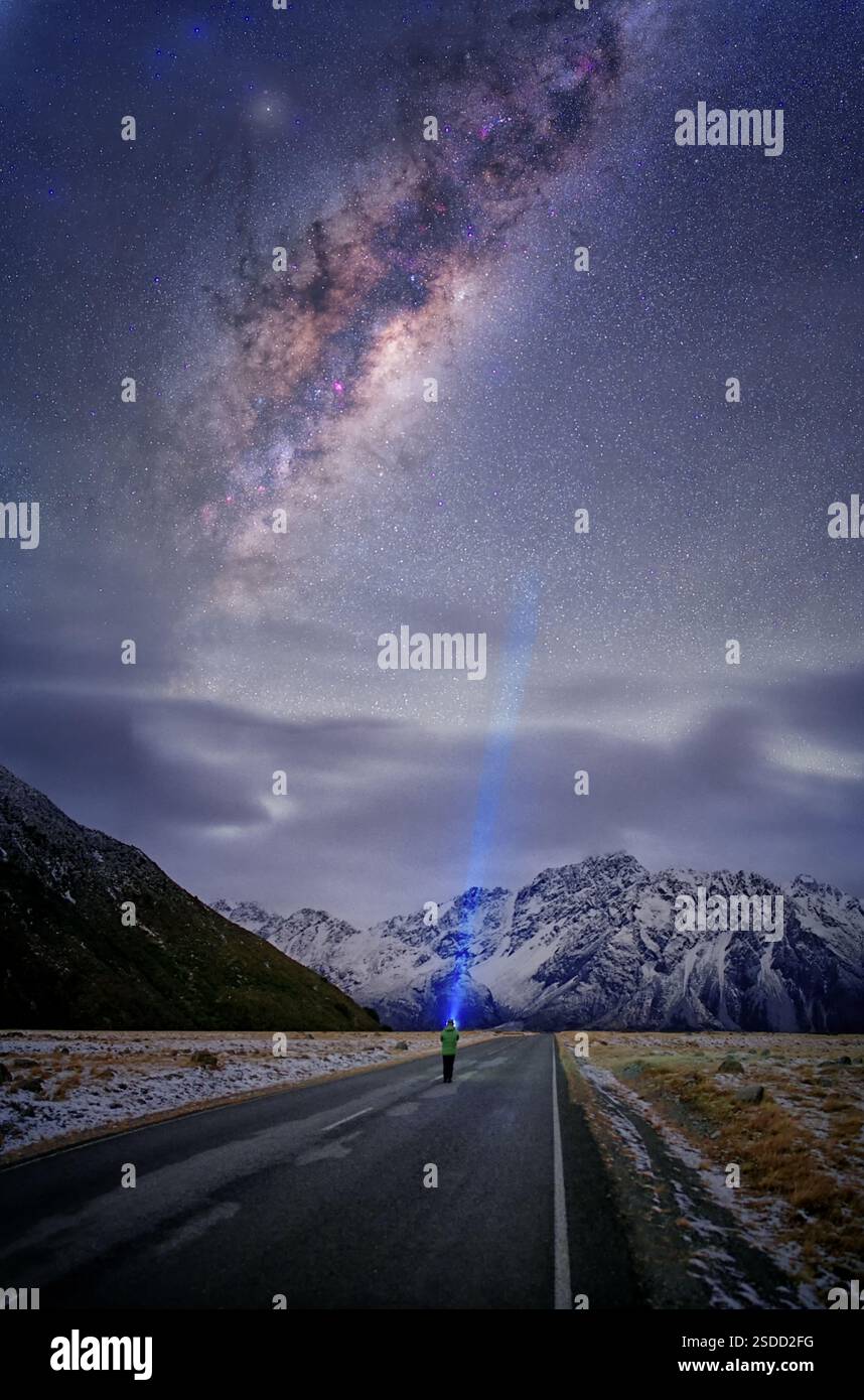 A lone figure stands on a road to the mountains with the core of the ...