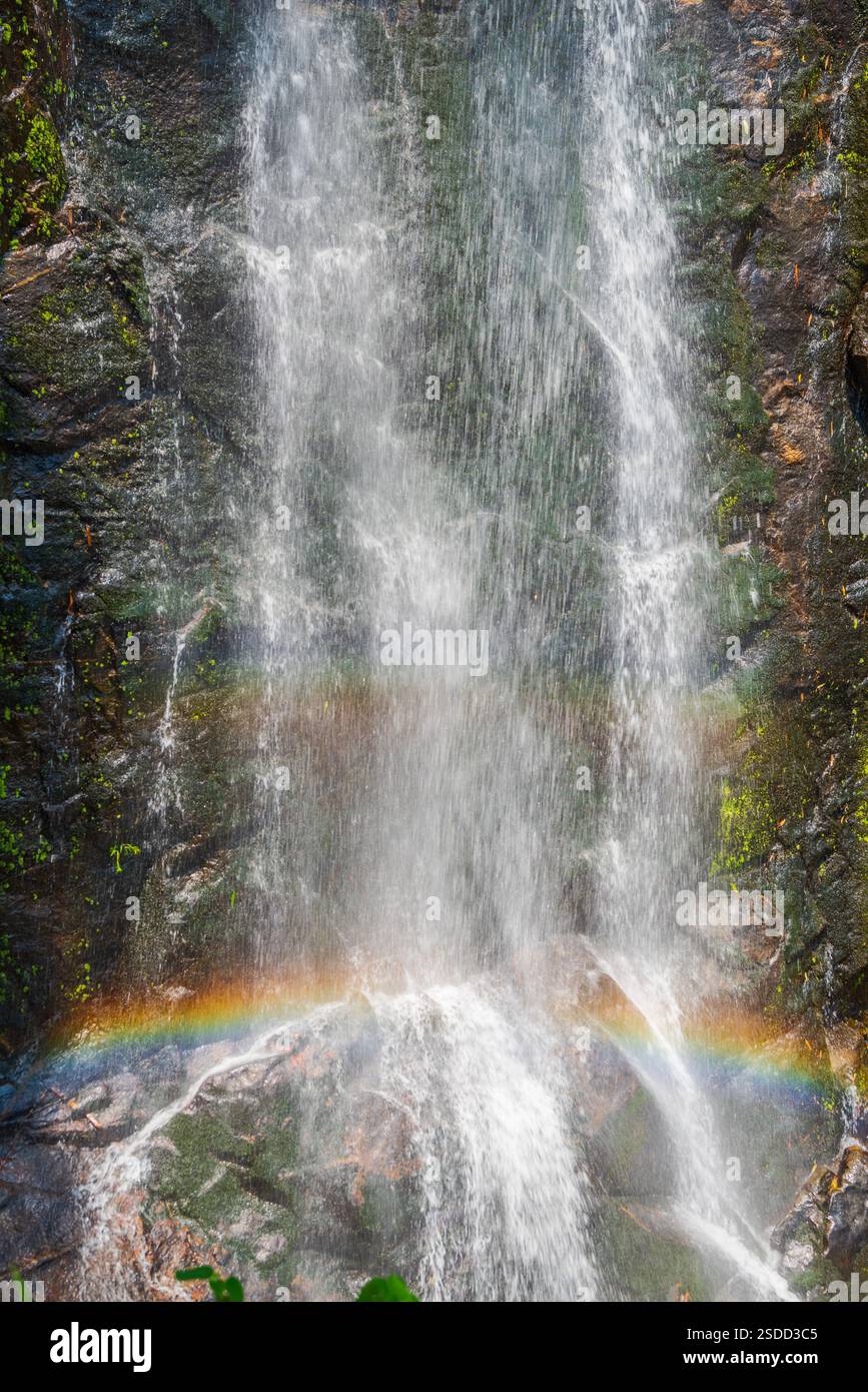Waterfall Cascading Down a Rocky Cliff with a Rainbow Stock Photo - Alamy