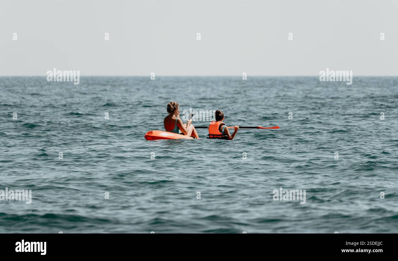 Two people enjoy a leisurely kayak ride on a calm ocean, with a clear ...