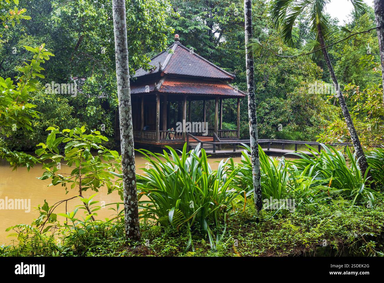 Woman seated in wooden pavilion beside lake at Tu Hieu Pagoda, Hue ...