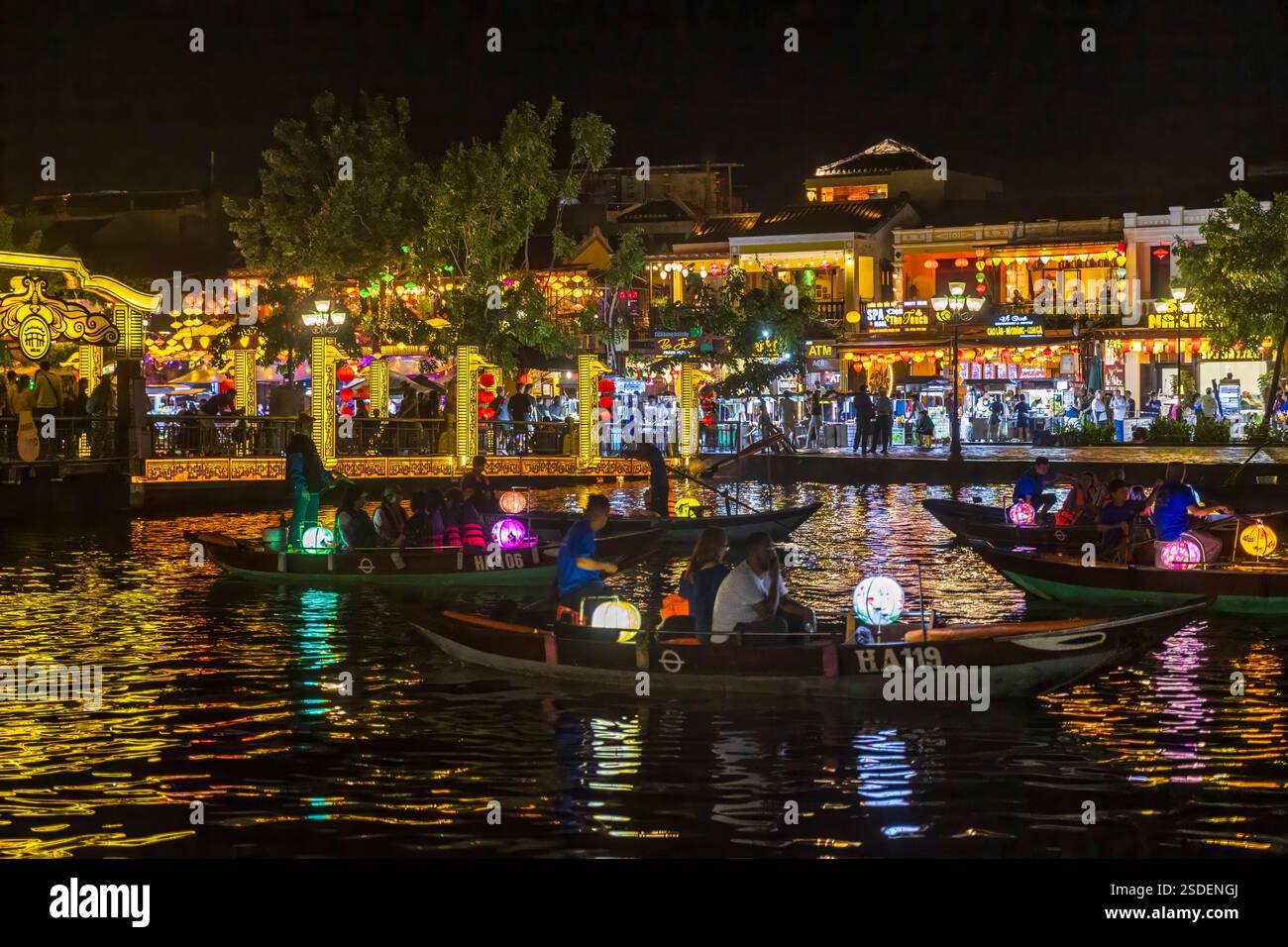 Small boats filled with people navigate a lively river in Hoi An ...