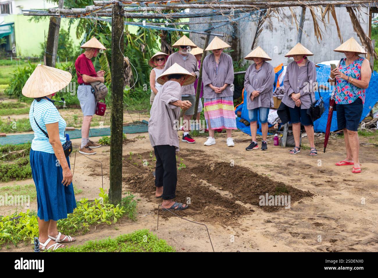 Tourists gather in a community garden to learn about traditional ...