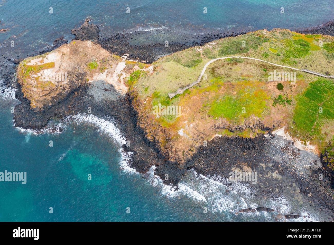 Aerial view of a coastal walking track over a rugged eroded coastline ...