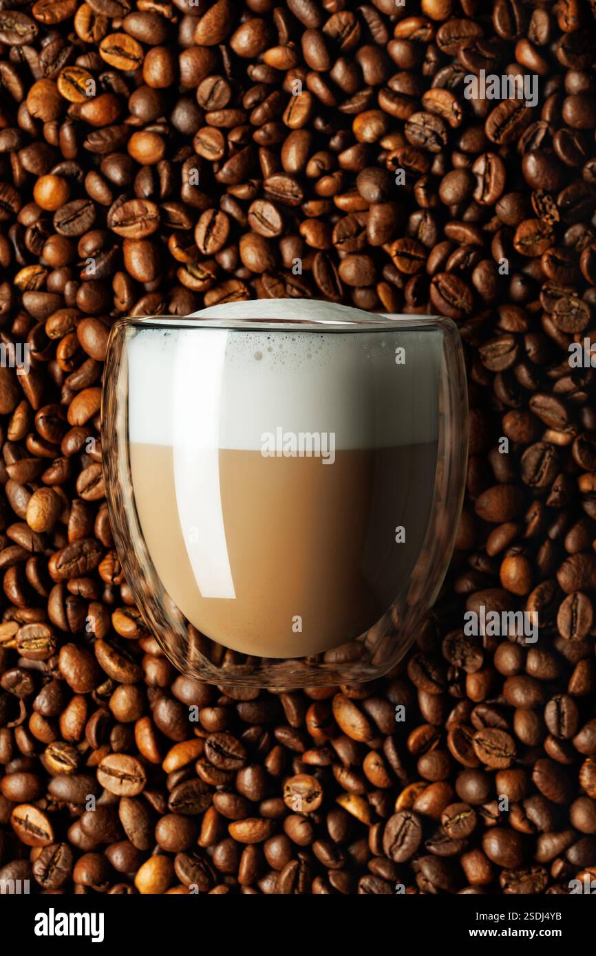 cappuccino with whipped milk cap in double wall glass and coffee beans ...