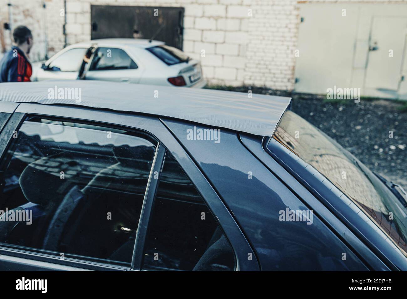 Two cars parked outdoors with one having its roof partially wrapped ...
