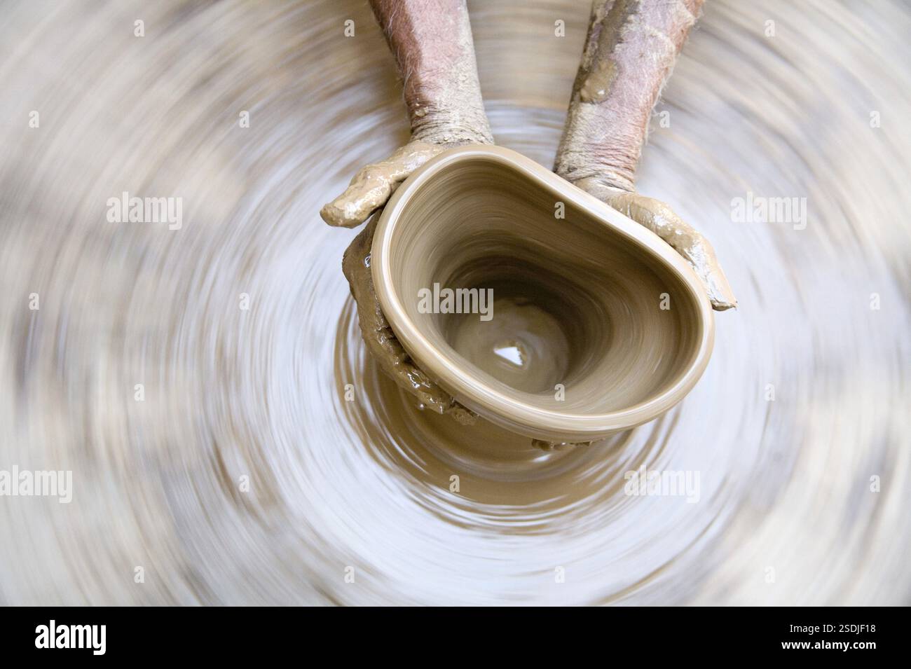 Pottery, artist muddy hands making clay pot giving shape on spinning ...