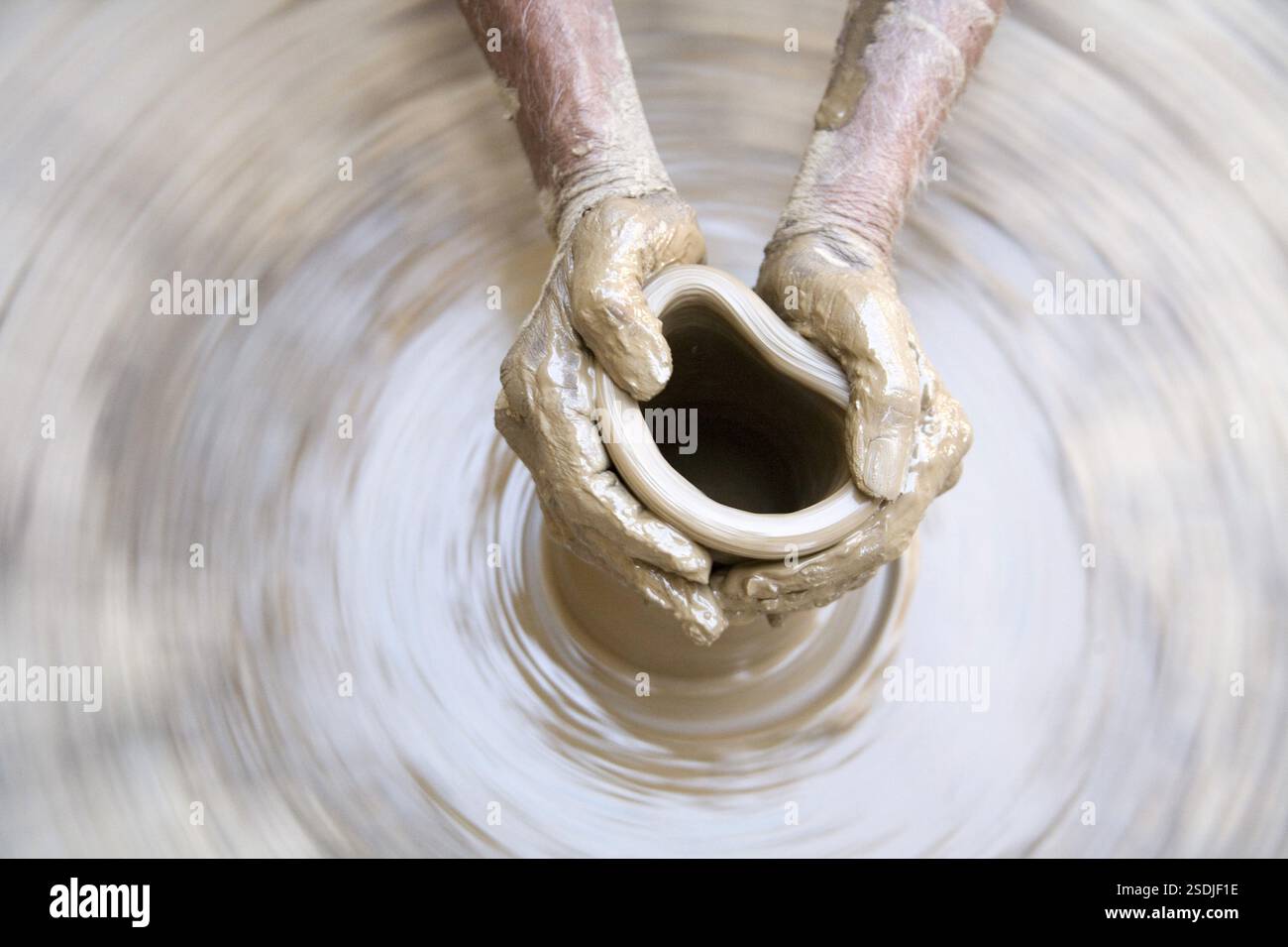 Pottery, artist muddy hands making clay pot giving shape on spinning ...