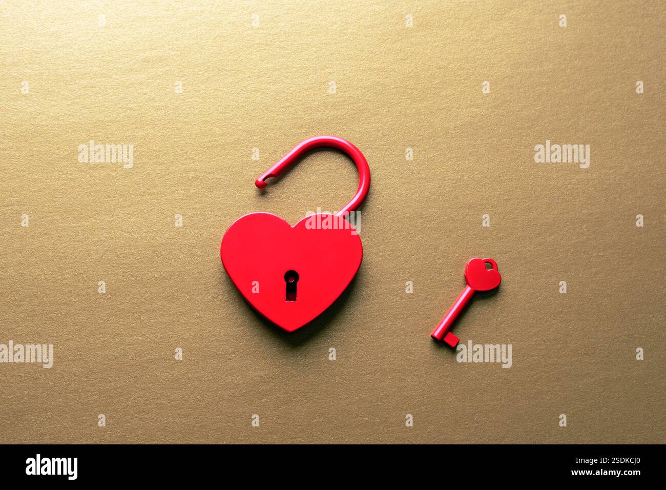 Red heart-shaped open padlock and matching key on a gold background ...