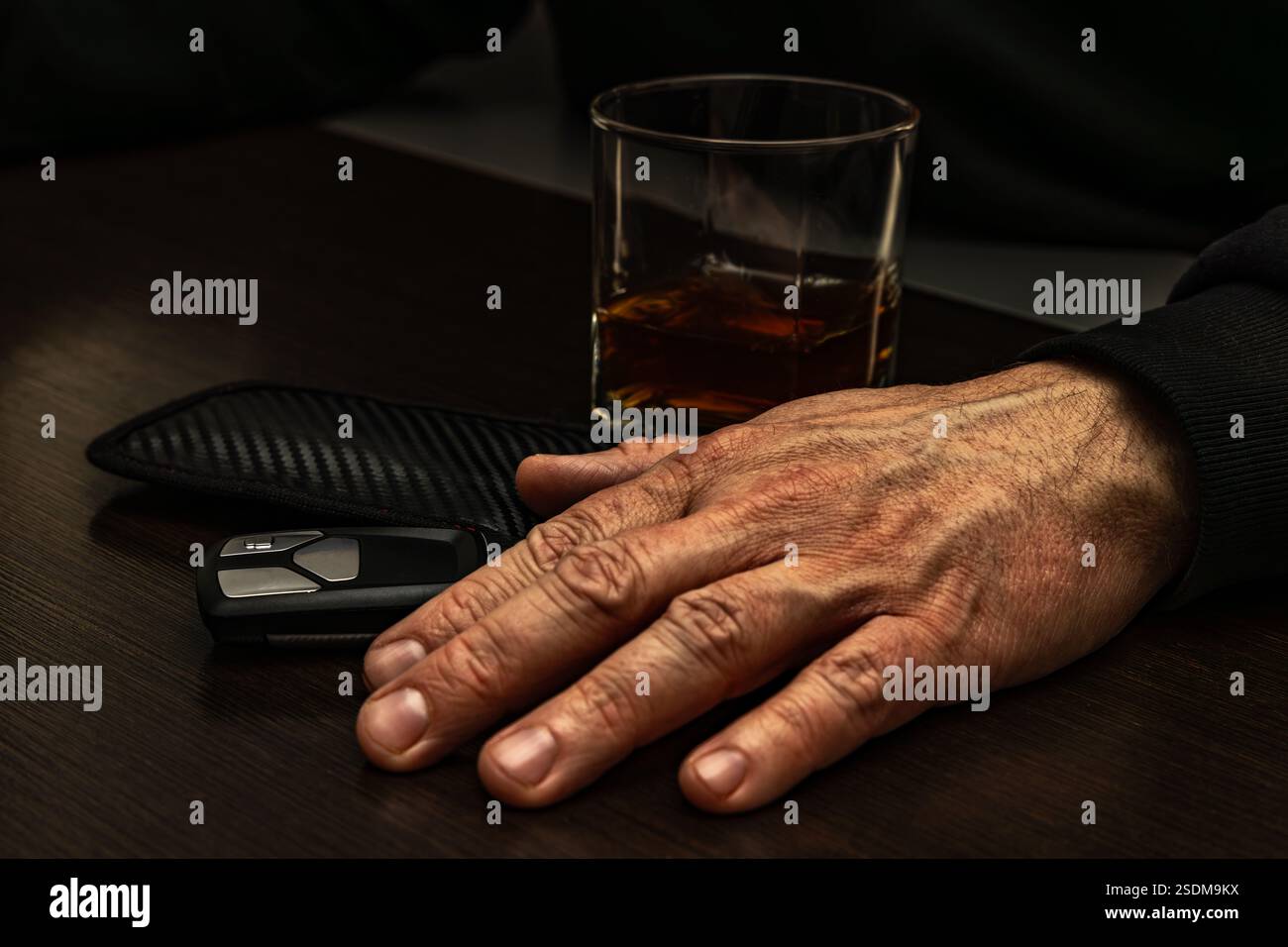 Drunk man lying on the table with a glass of alcohol, car keys on the ...