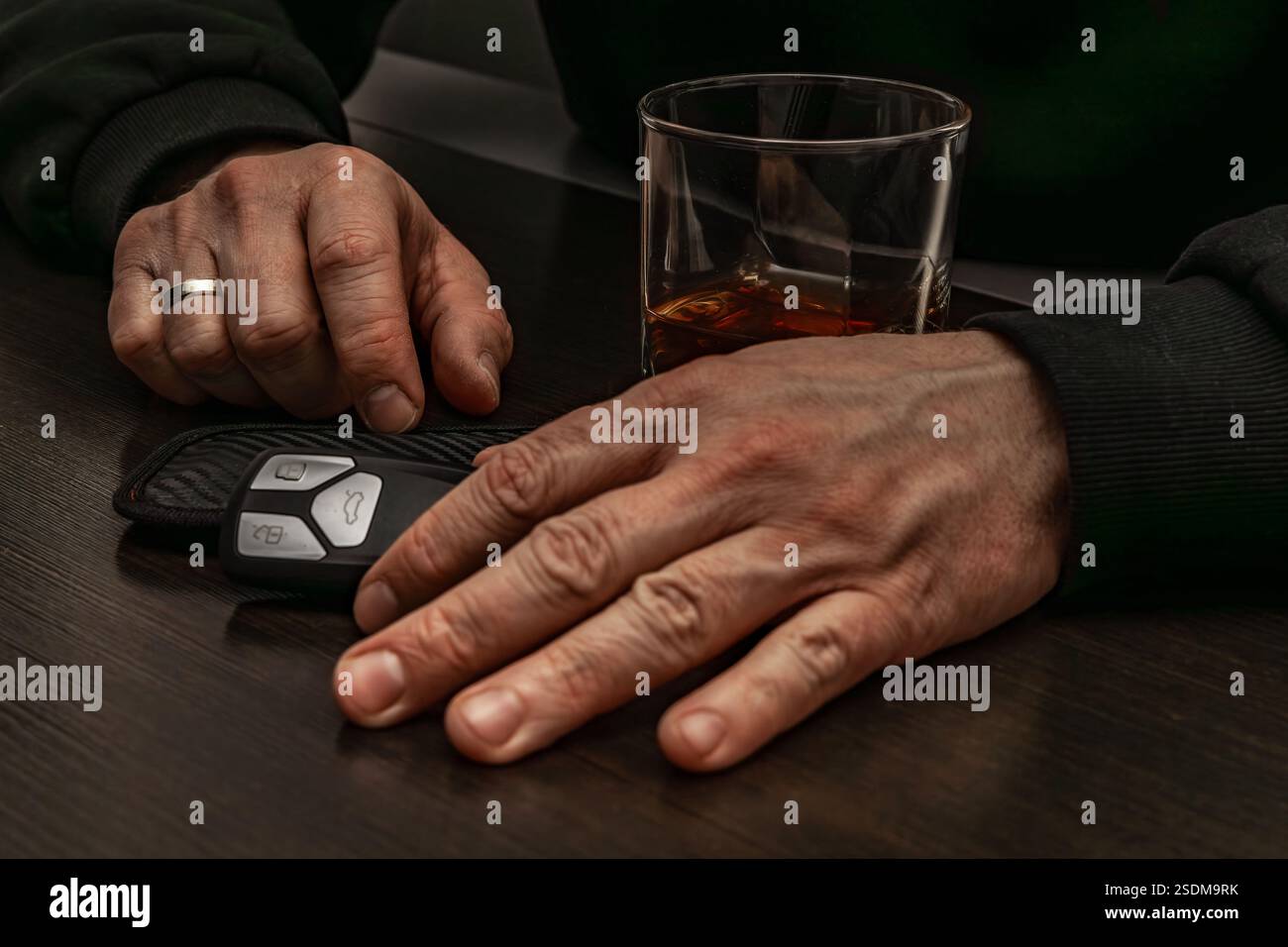 Drunk man lying on the table with a glass of alcohol, car keys on the ...