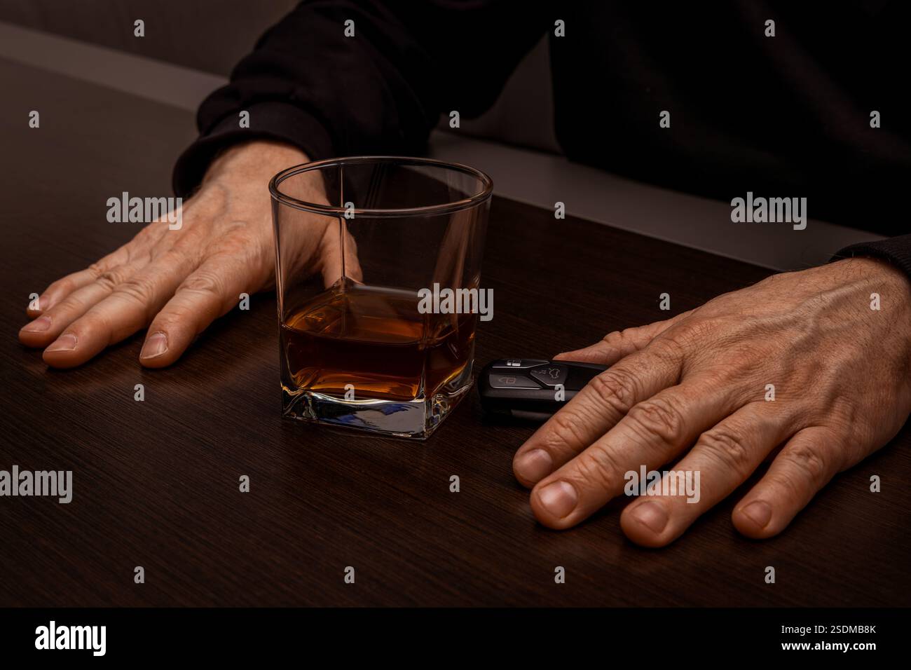 Drunk man lying on the table with a glass of alcohol, car keys on the ...