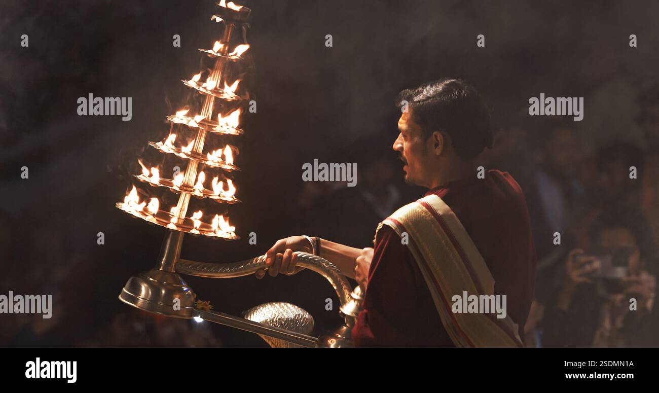 Varanasi, India. Man makes movements with a candle holder with lit ...