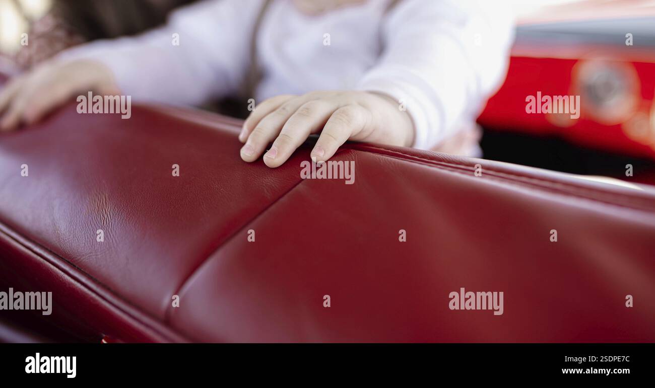 Child lightly grasping onto the red leather of a car's interior Stock ...