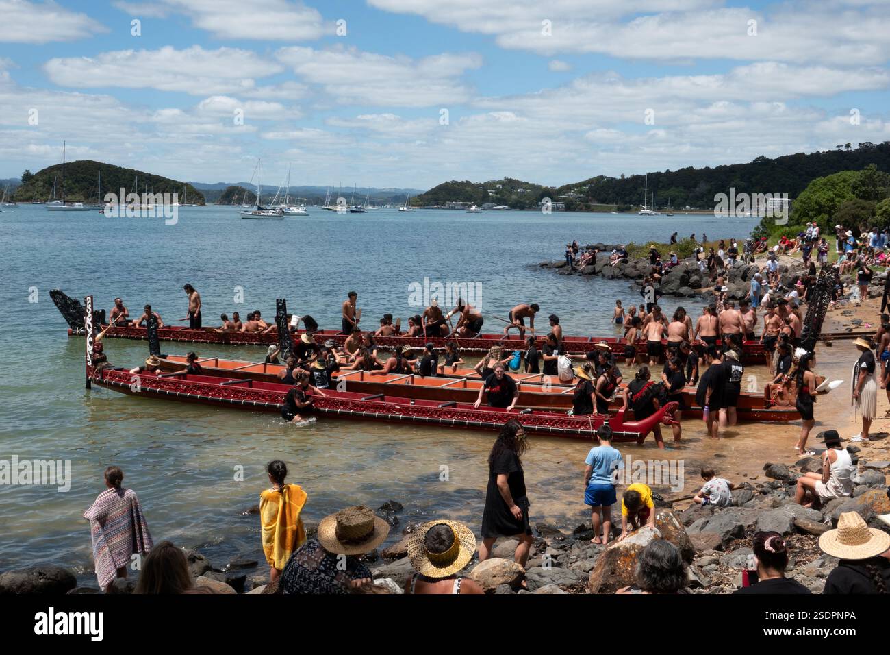 Traditional Maori waka and people on beach during Waitangi Day ...