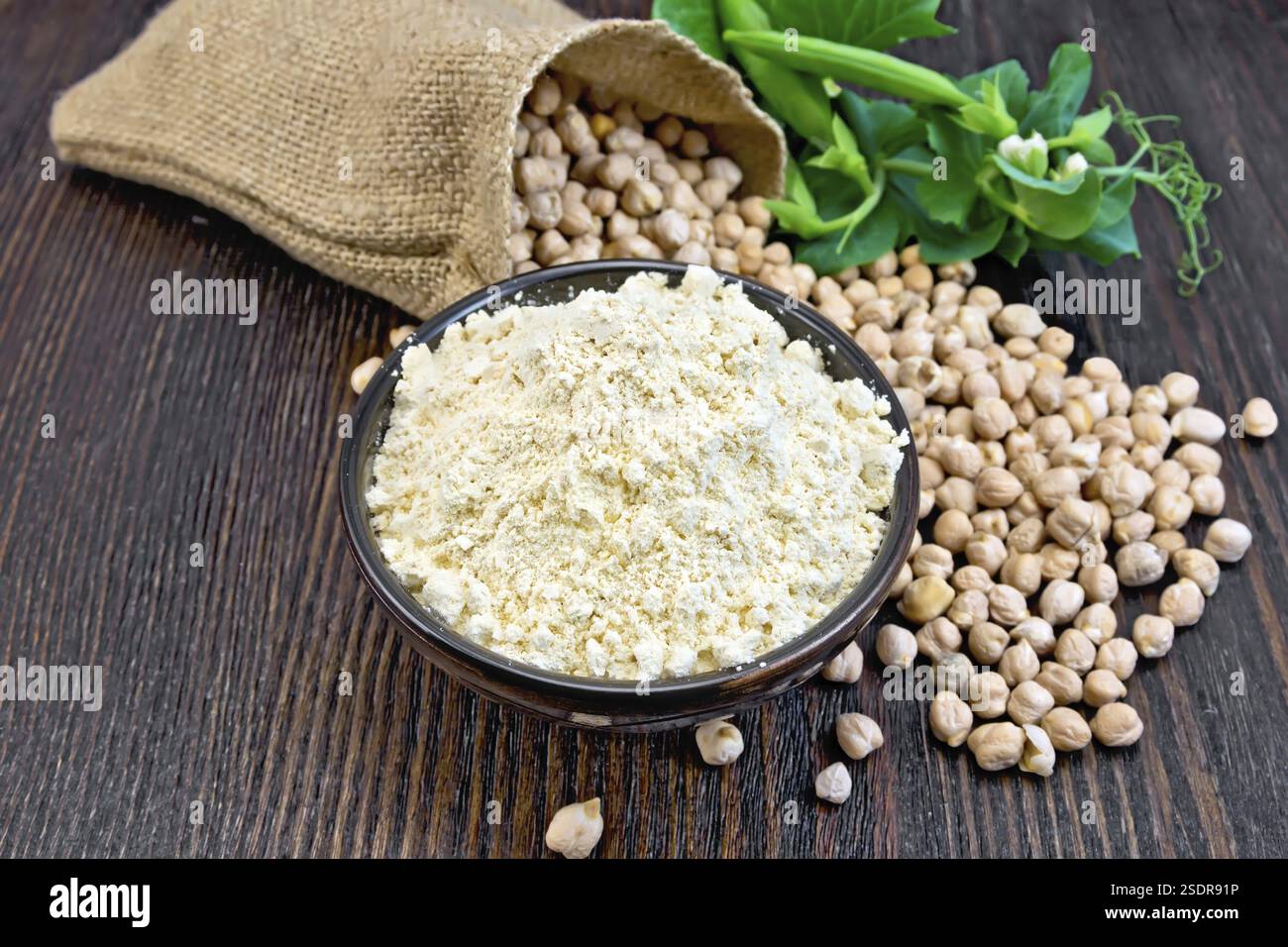 Flour chickpeas in a bowl, chick-peas in a sack and fresh pea pods on a ...