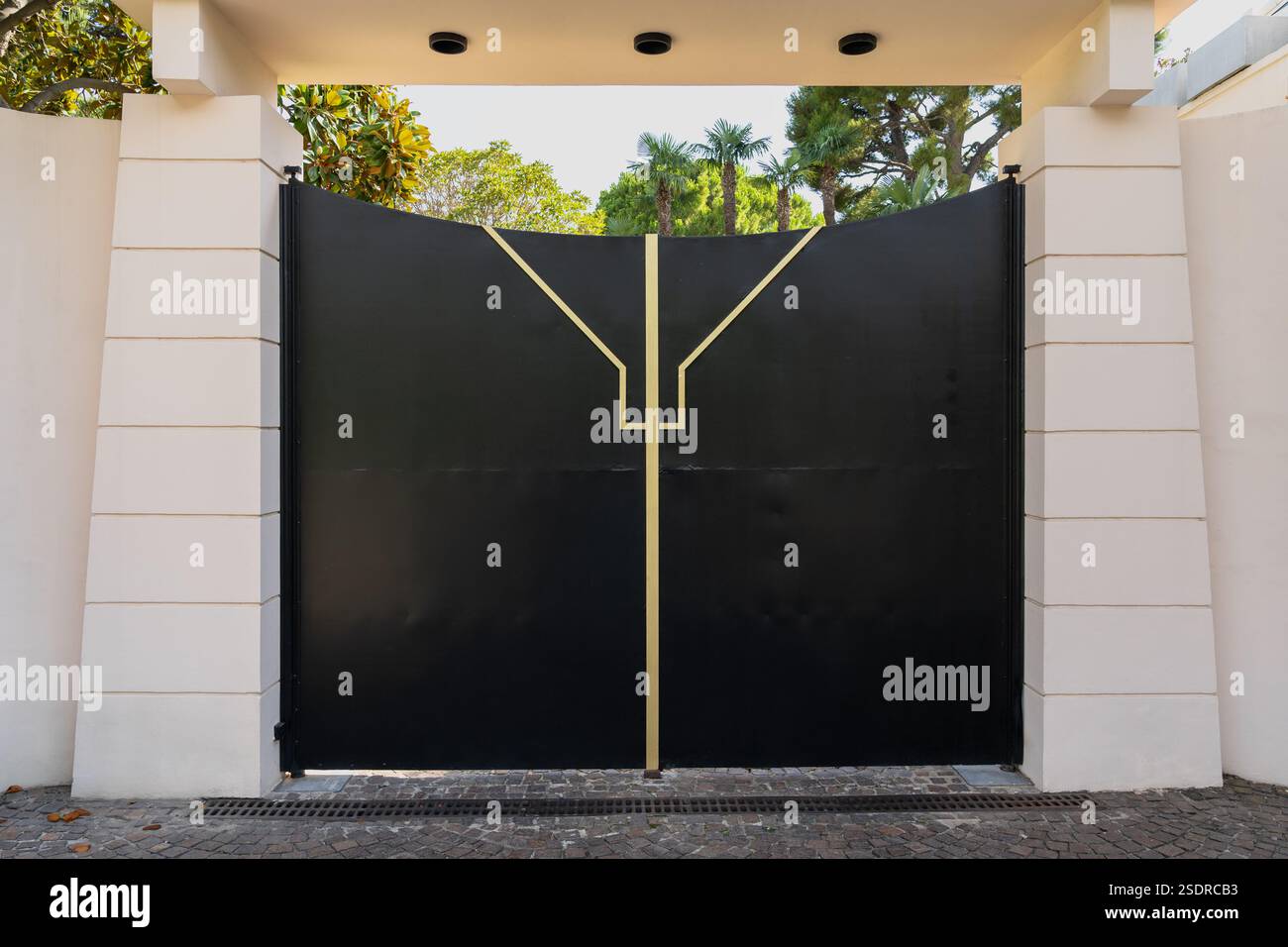 Elegant black gates with gold decorative elements in the sunny ...