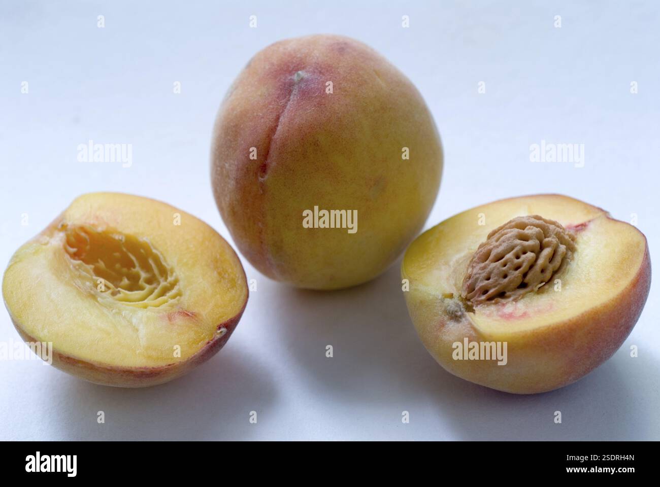 Peaches two cut in half fruits white background Stock Photo - Alamy