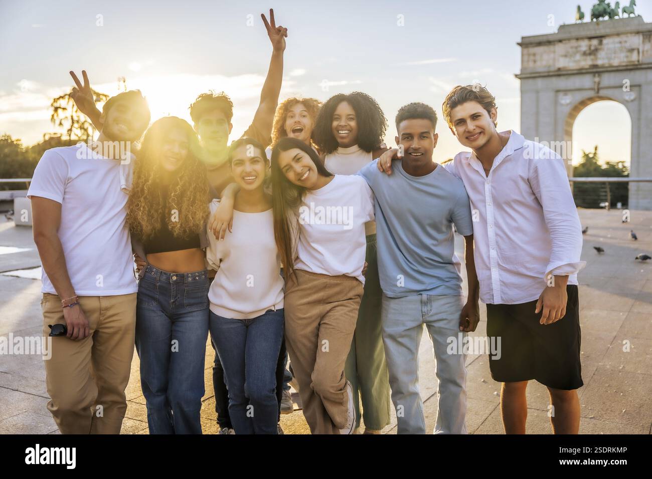 Portrait of multi-ethnic friends embracing and raising arms happily ...