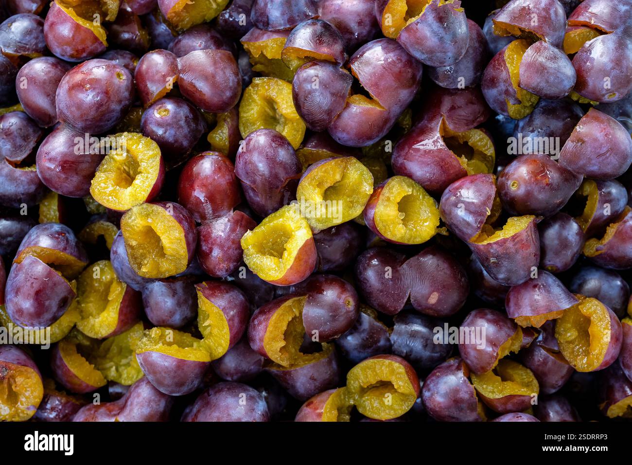 Hand-pitted raw plums close-up, top view. Purple color plums background ...
