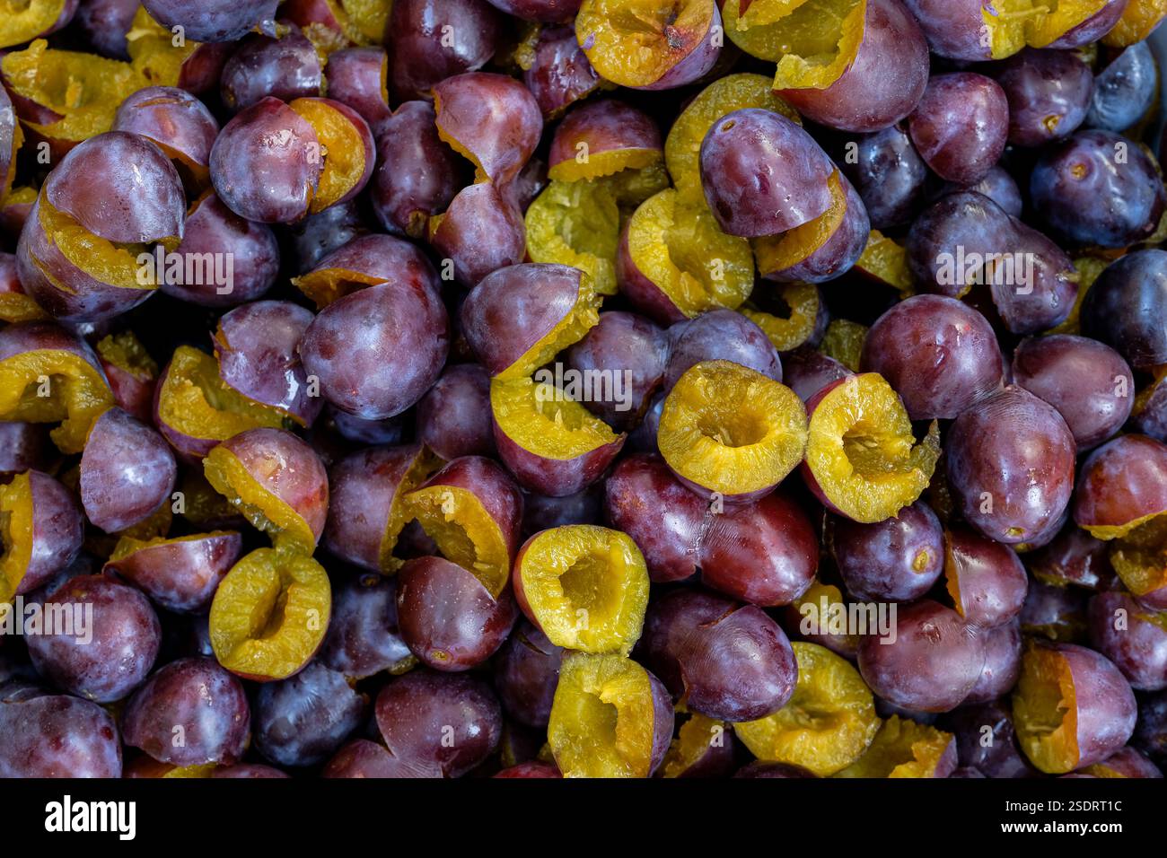 Hand-pitted raw plums close-up, top view. Purple color plums background ...