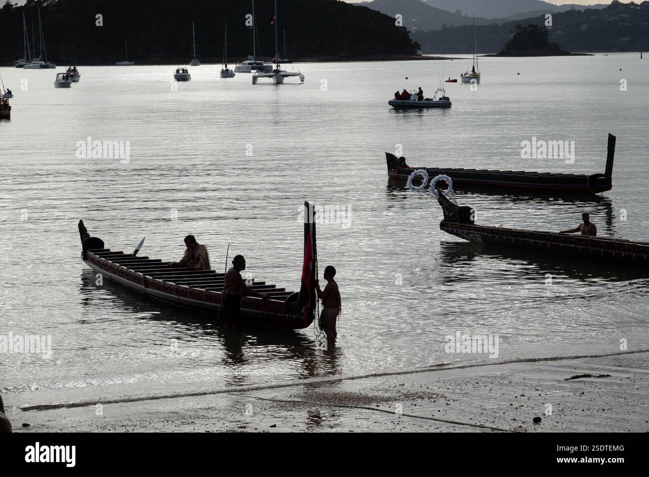 Traditional Maori waka and people on beach during Waitangi Day ...
