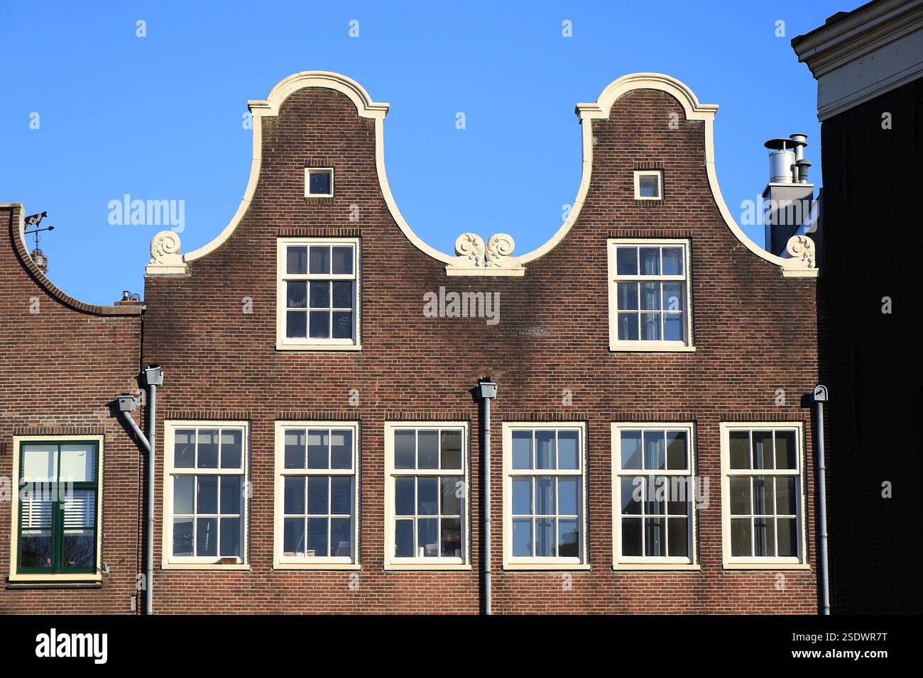 Typical Dutch brick house facades with clock gables close up with blue ...