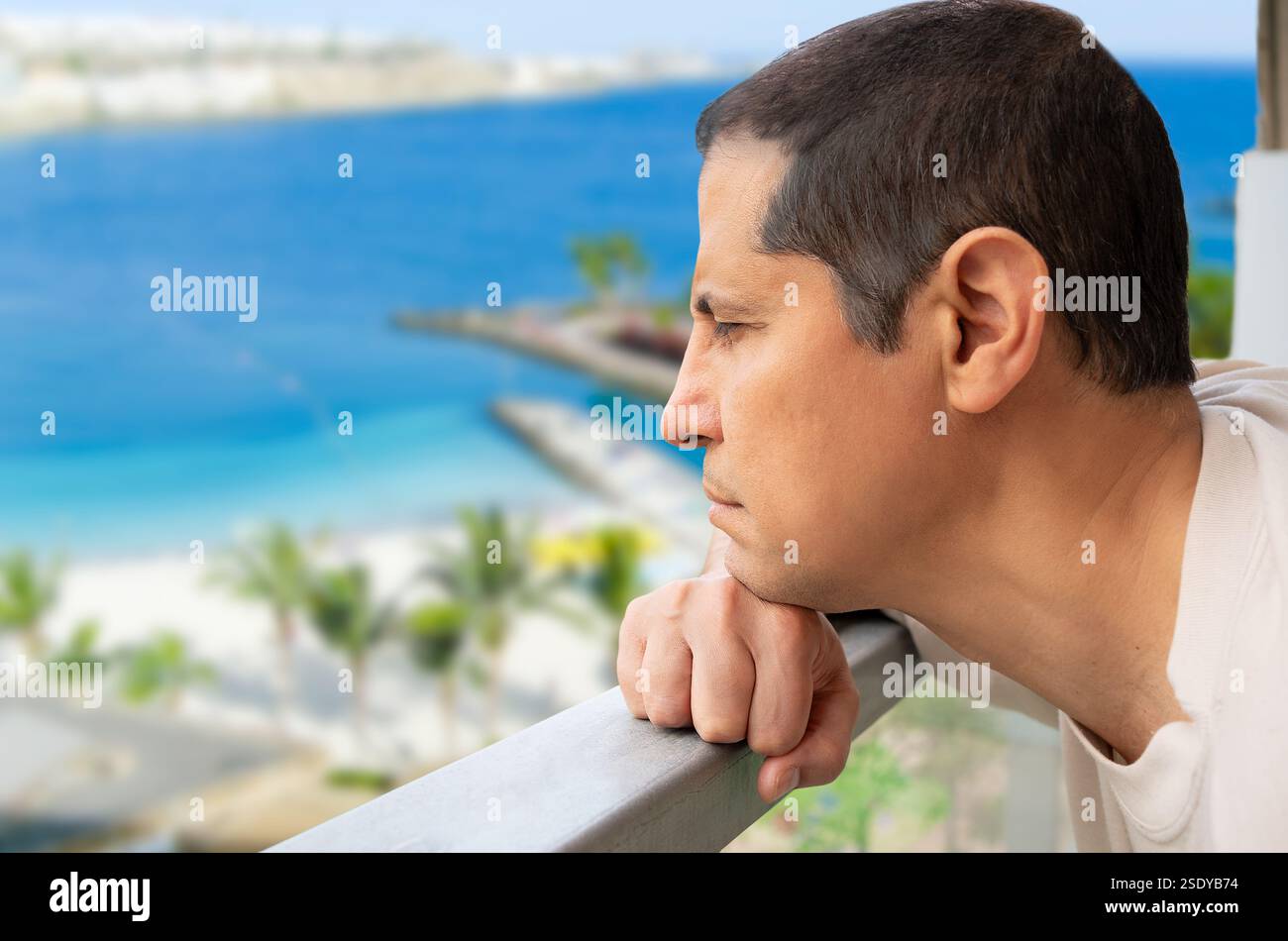 Side view portrait of a sad single man looking down from a balcony of a ...