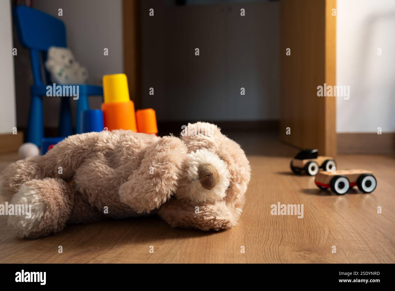 A teddy bear lying on the floor of a child's bedroom at night with an ...