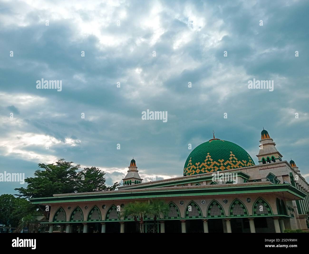 A mosque roof in cream and green under a blue sky with white clouds and ...