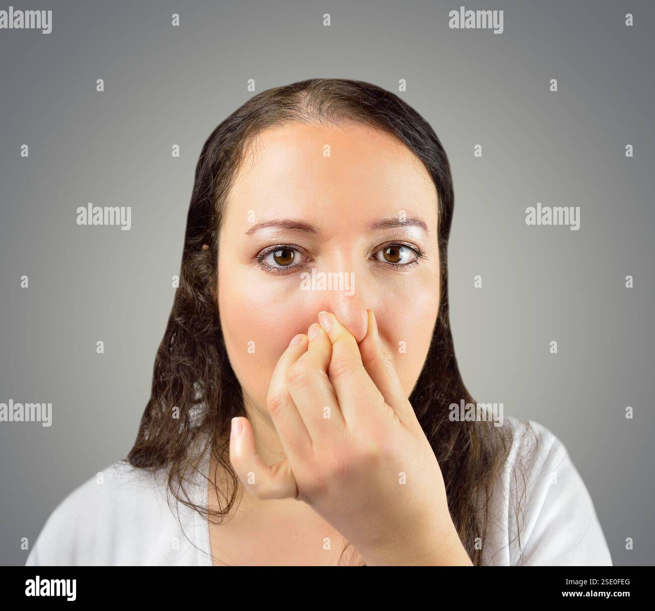 woman holding his nose smelling stink isolated on a grey background ...