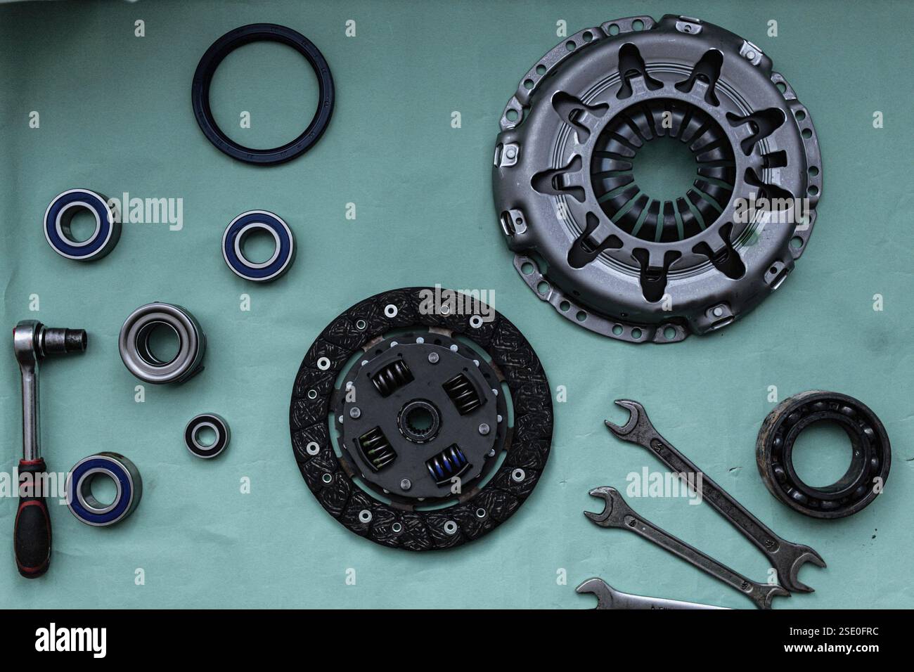 Various car parts including clutch components and tools laid out on a ...