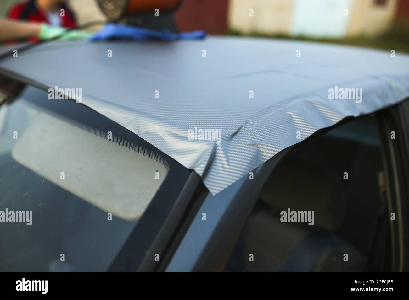 Process of applying a wrapping film on a car's roof with visible hands ...
