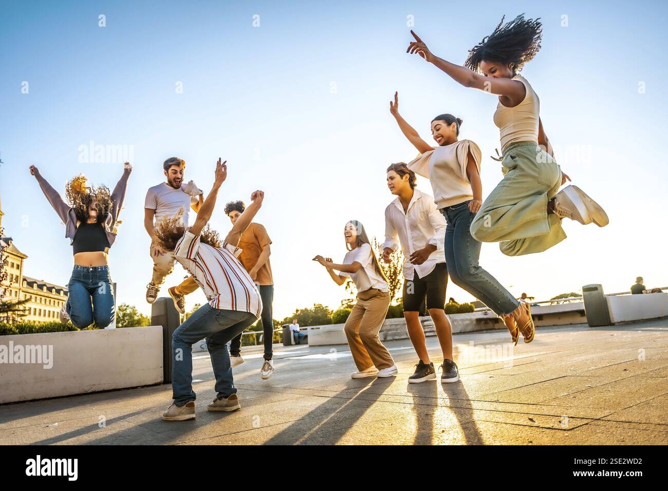 Full length photo of a group of multiracial friends jumping and dancing ...