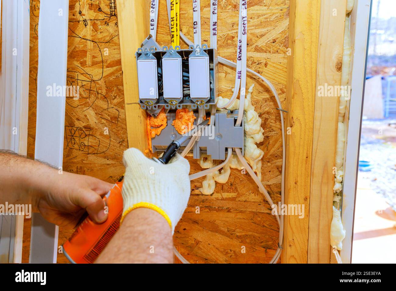 Contractor with spray foam insulation electrician connects wires to ...