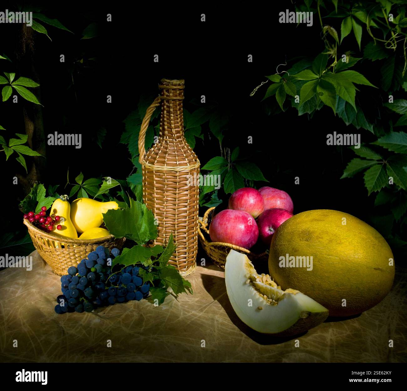 Still life with a bottle of wine, melon, grapes and apples against a ...
