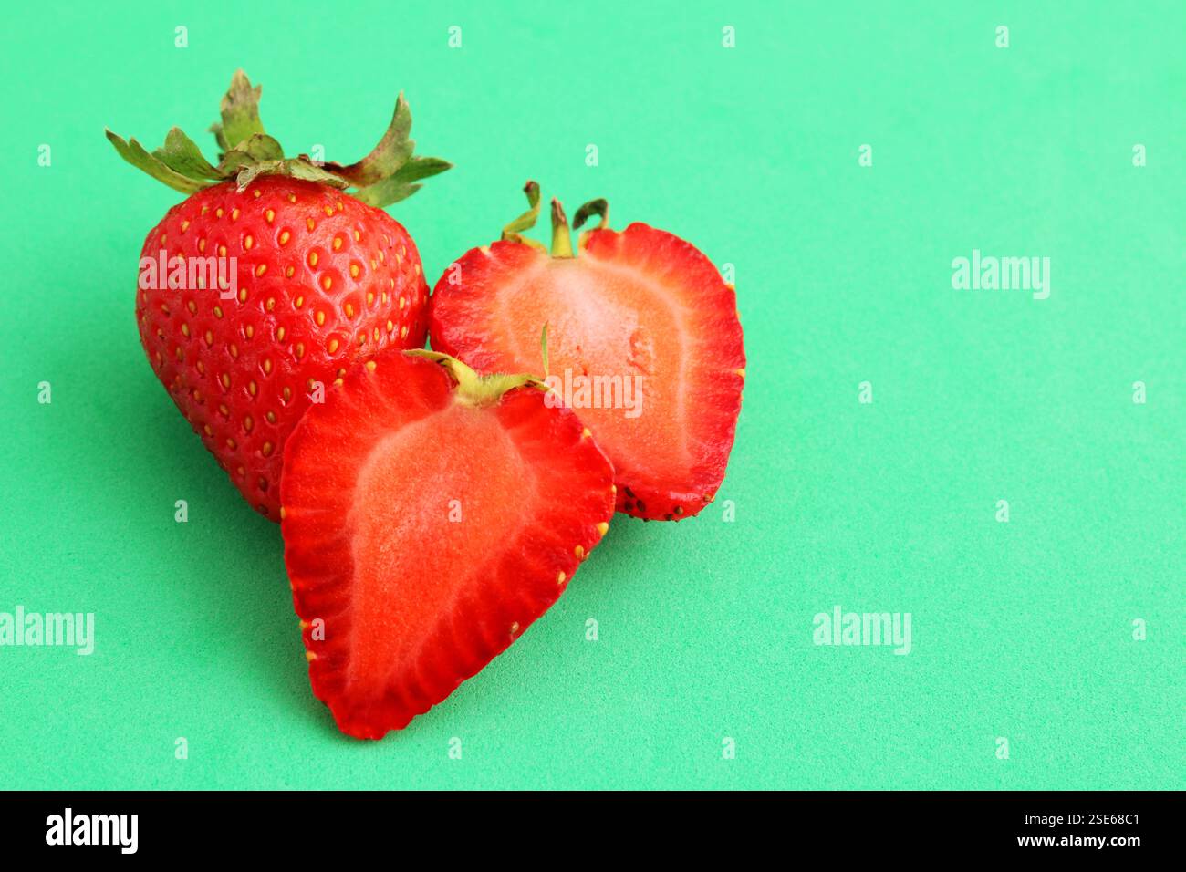 Two ripe strawberries, one of them cut in half Stock Photo - Alamy