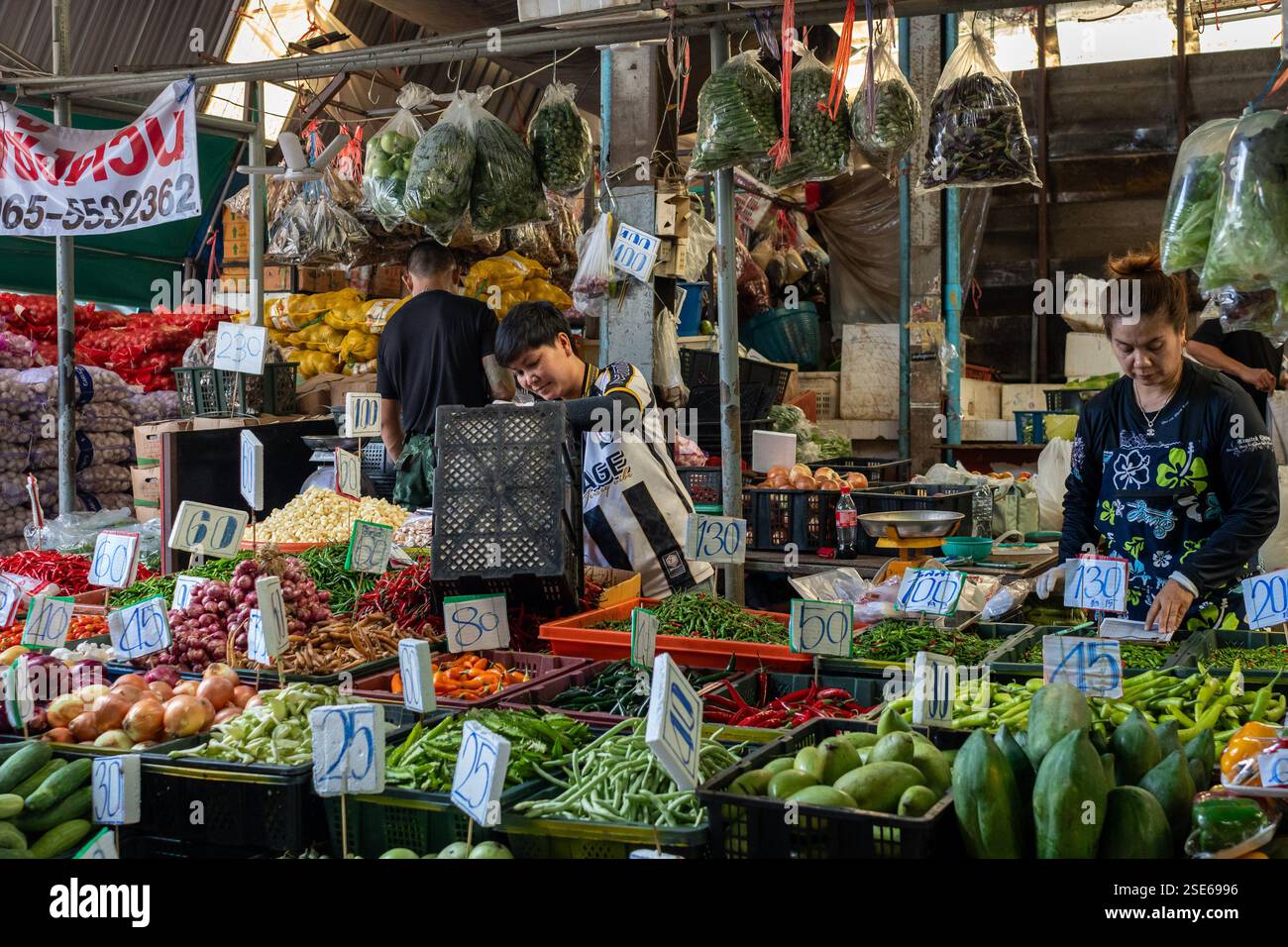 A woman is seen adding vegetables to her stall at Bangkapi Market ...