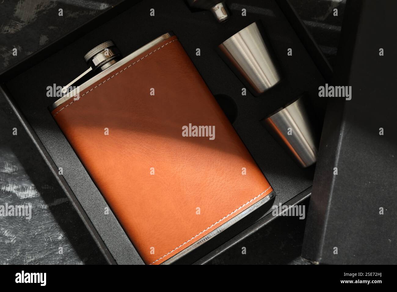 Hip flask, cups and funnel in package on dark table, top view Stock ...