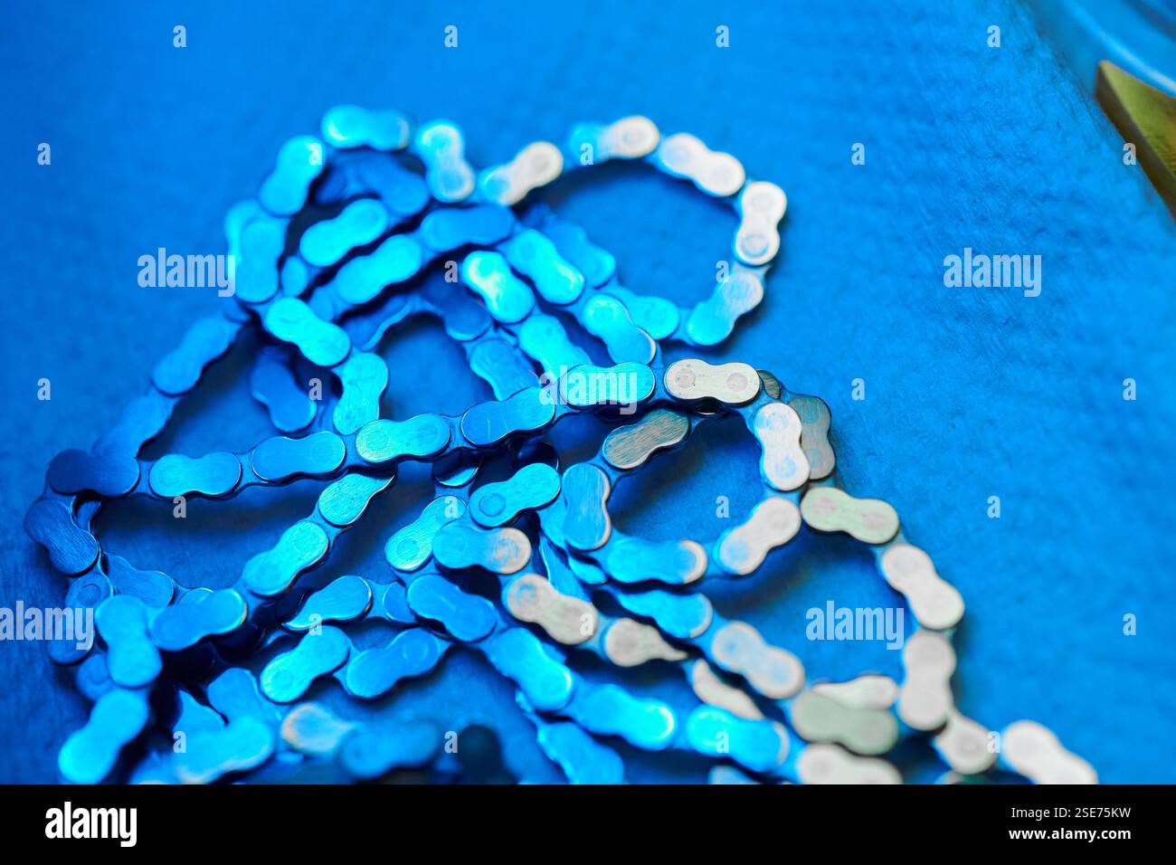 Intricate steel chain of a clock mechanism glimmers in vivid blue light ...