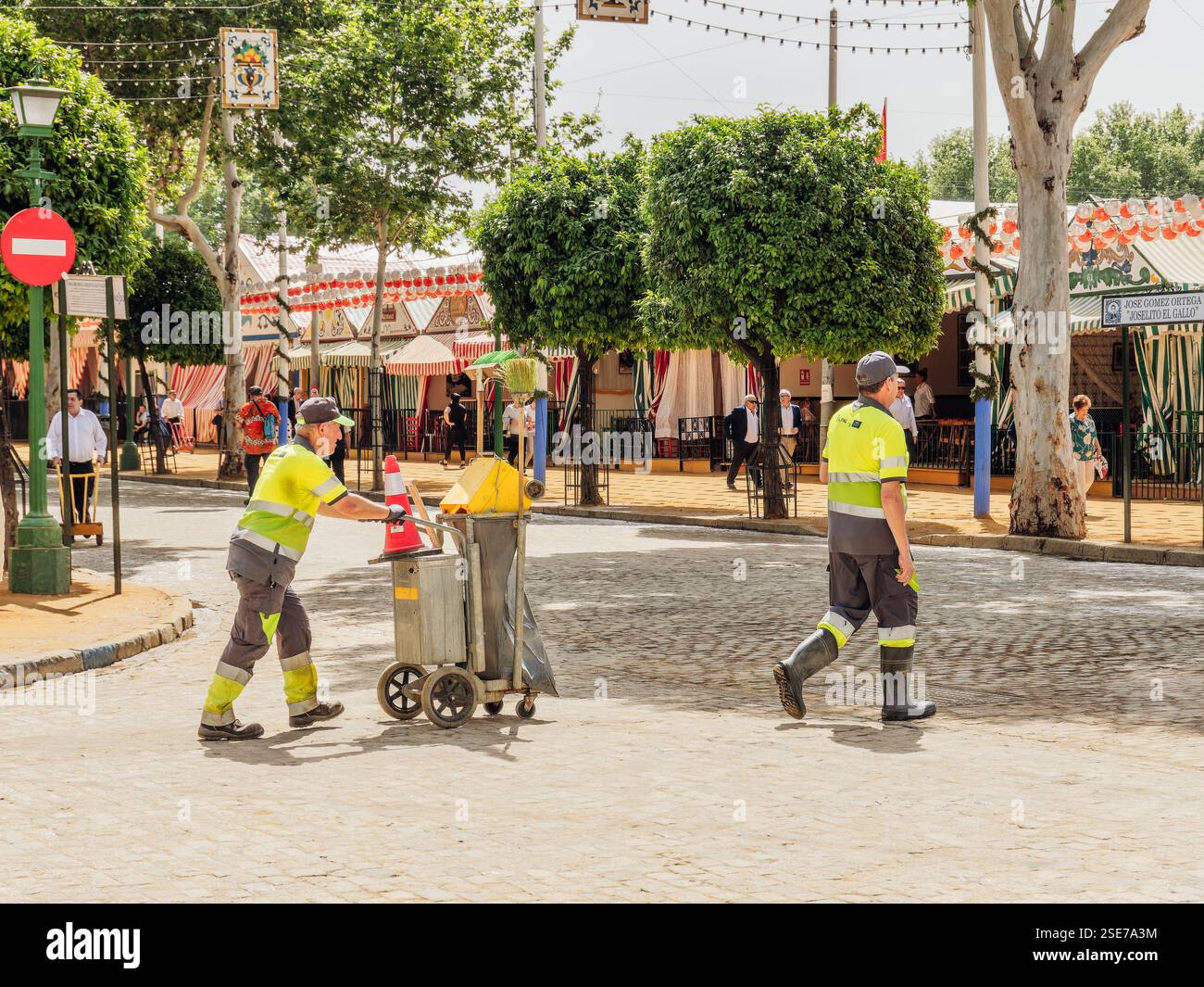 Two sanitation workers in high-visibility uniforms clean the streets during the Seville Fair ...