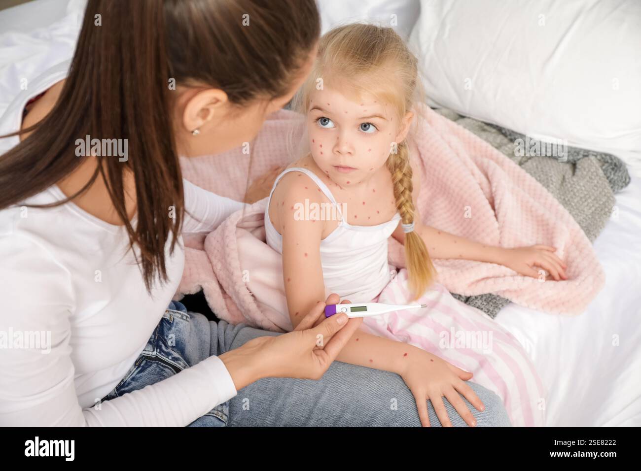 Mother giving thermometer to her little daughter ill with chickenpox in ...