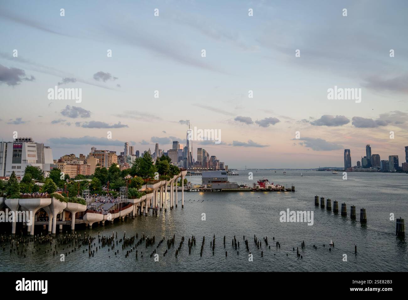 The city skyline stretches along the waterfront as the sun sets behind ...