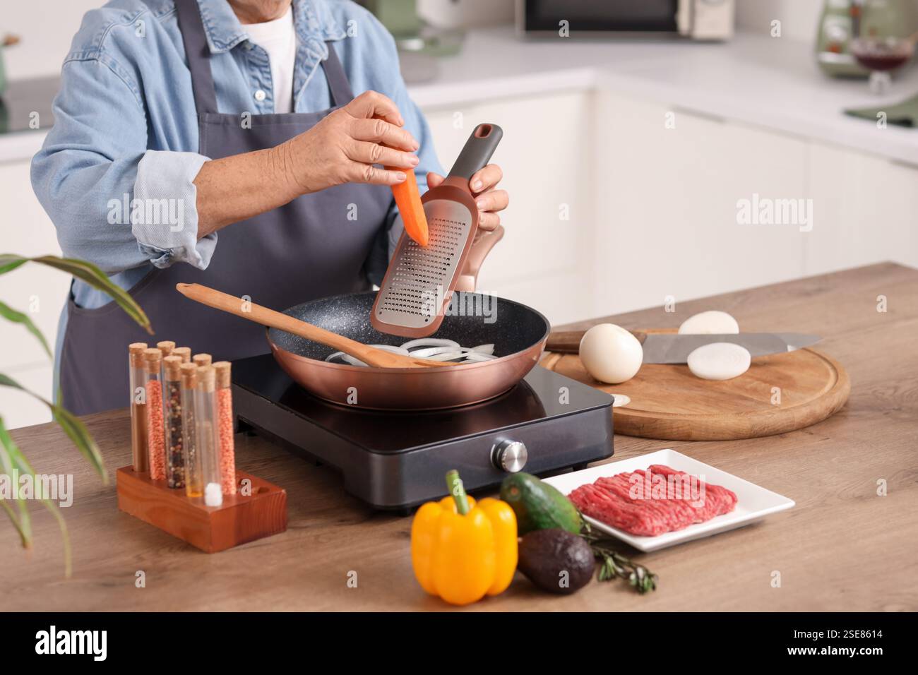 Senior woman frying vegetables in kitchen Stock Photo - Alamy