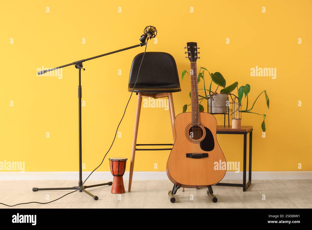 Stool and table with musical instruments near yellow wall in room Stock ...
